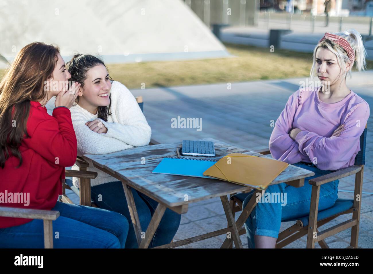 Unhappy girl being gossiped about two friends Stock Photo - Alamy