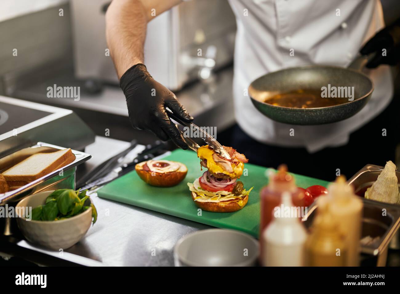 Crop view of chef's hands, putting juicy grilled beef with melted ...