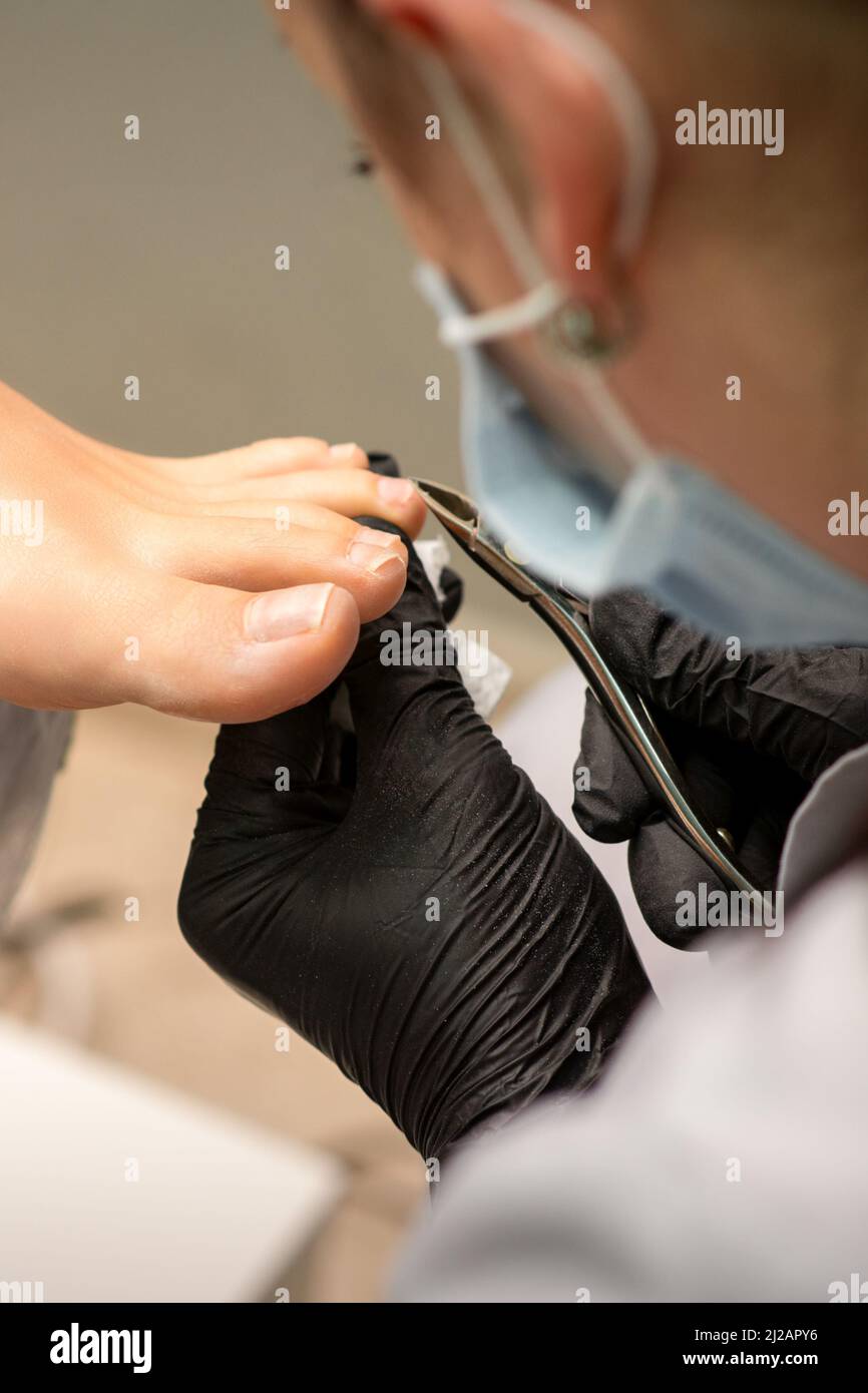 Pedicure master using nail nippers while trimming toenails in a ...