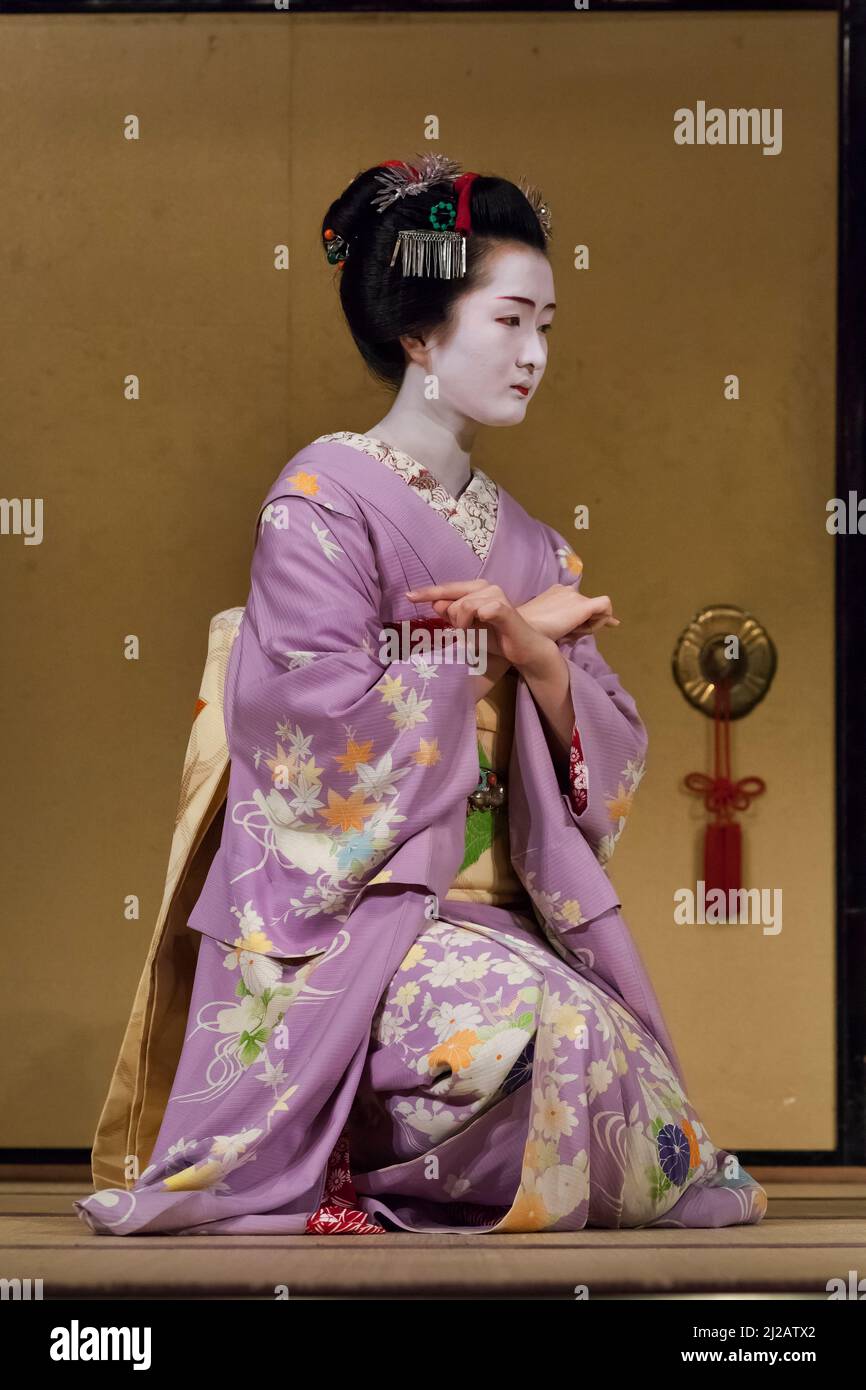 Vertical close-up view of a seated geisha wearing a kimono in a ...