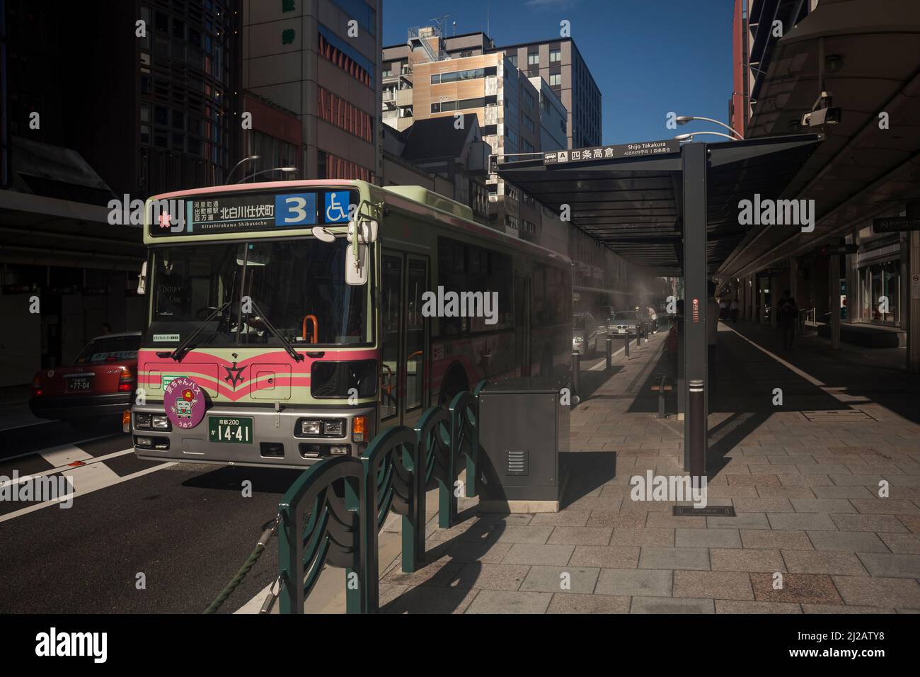 Horizontal view of a steaming urban bus on a bus stop in Downtown Kyoto ...