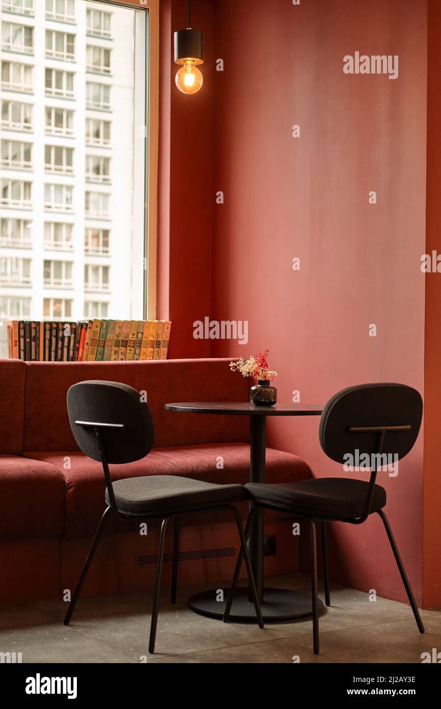Two chairs and table in modern cafe with red walls and red couch ...