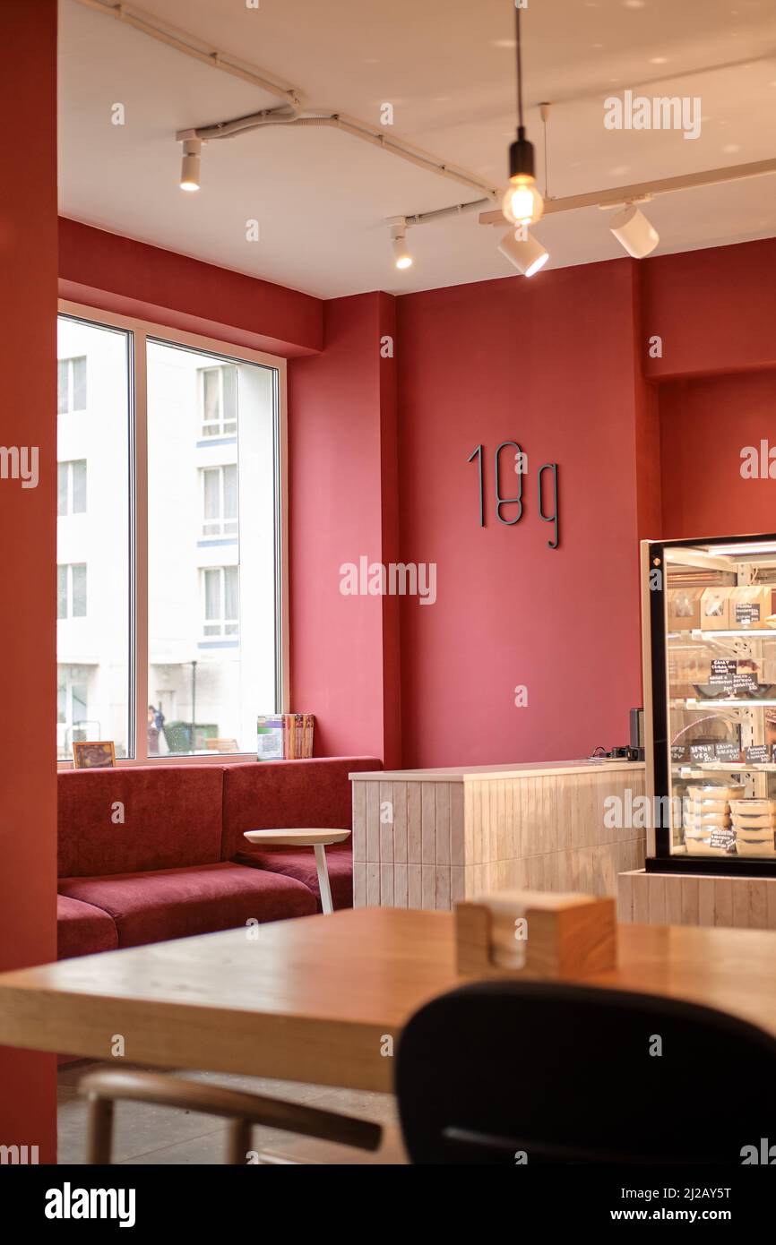 Modern cafe with red walls and red couch. Books on windowsill. Window ...