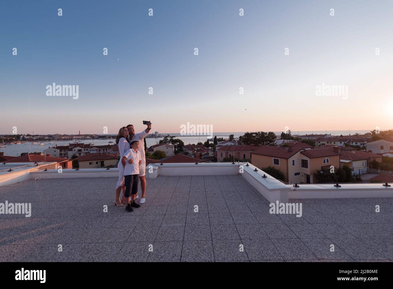 Happy family taking a selfie with a smartphone on the roof of their ...