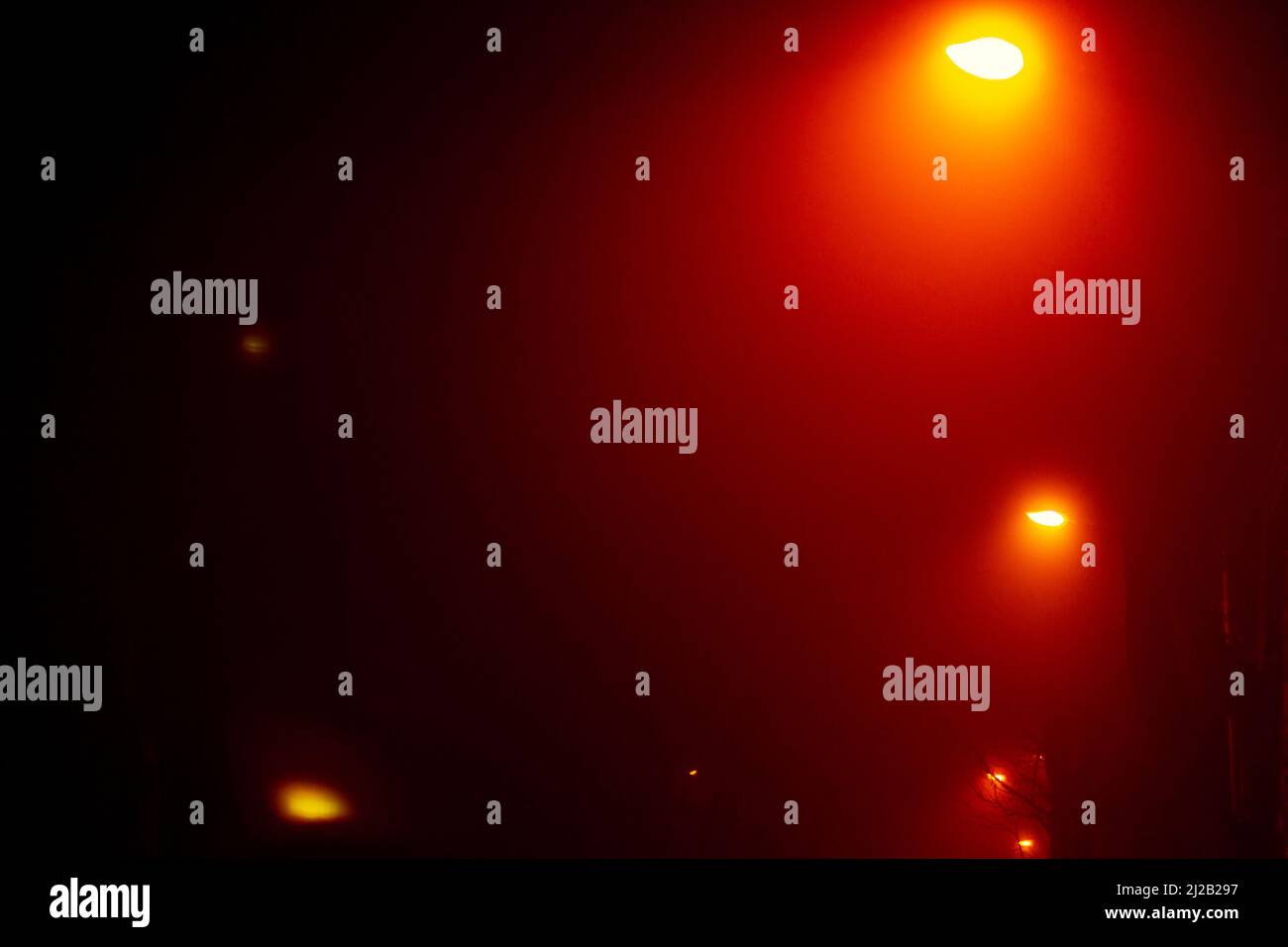 Street light illumination in the foggy night . Red haze in the ...