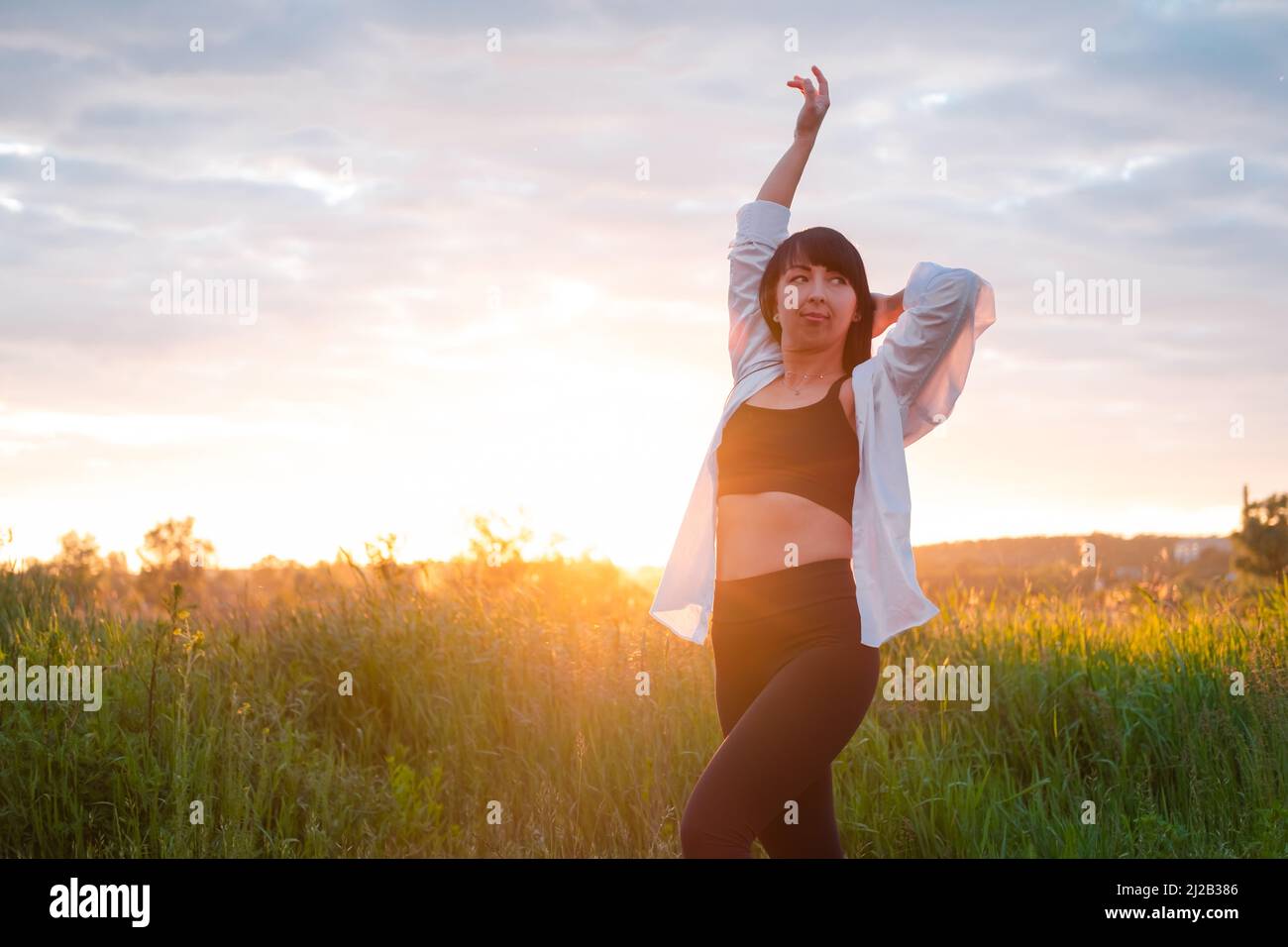pretty young woman in white blouse on summer green field on sunset ...