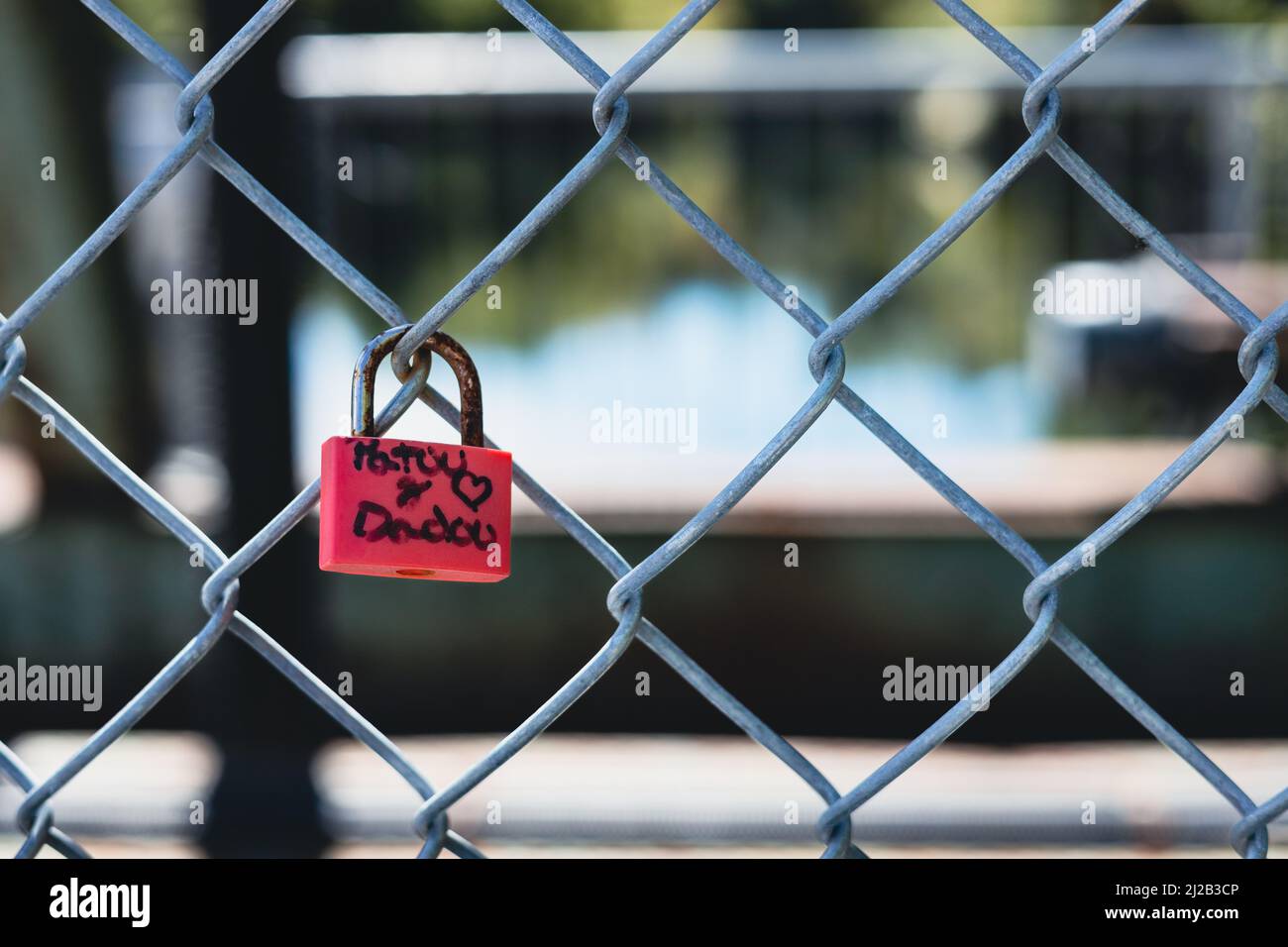 A closeup shot of a red love lock with names on a gate Stock Photo - Alamy