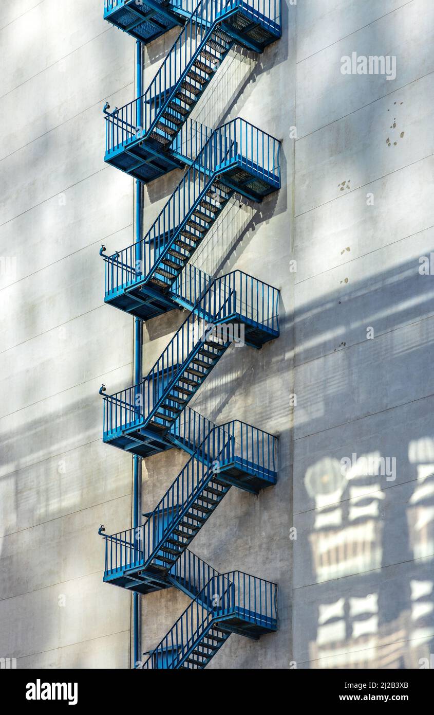 Blue emergency fire stairs metal construction aside plain concrete wall ...