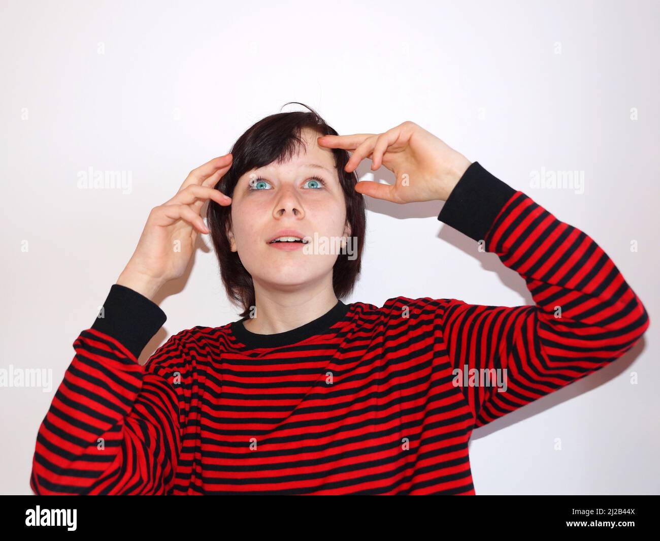 portrait of a surprised scared teen girl with blue eyes on a white ...