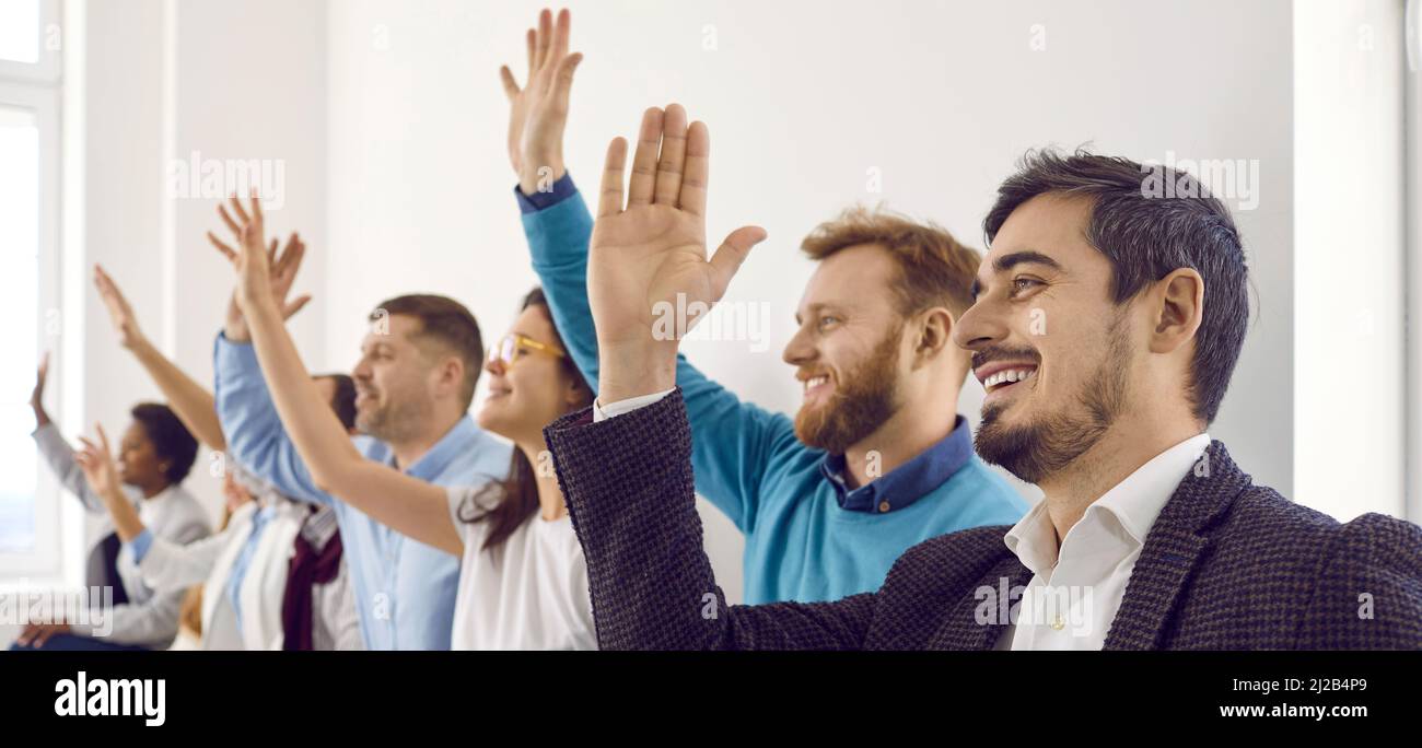 Group of happy people raising their hands up to ask questions at ...