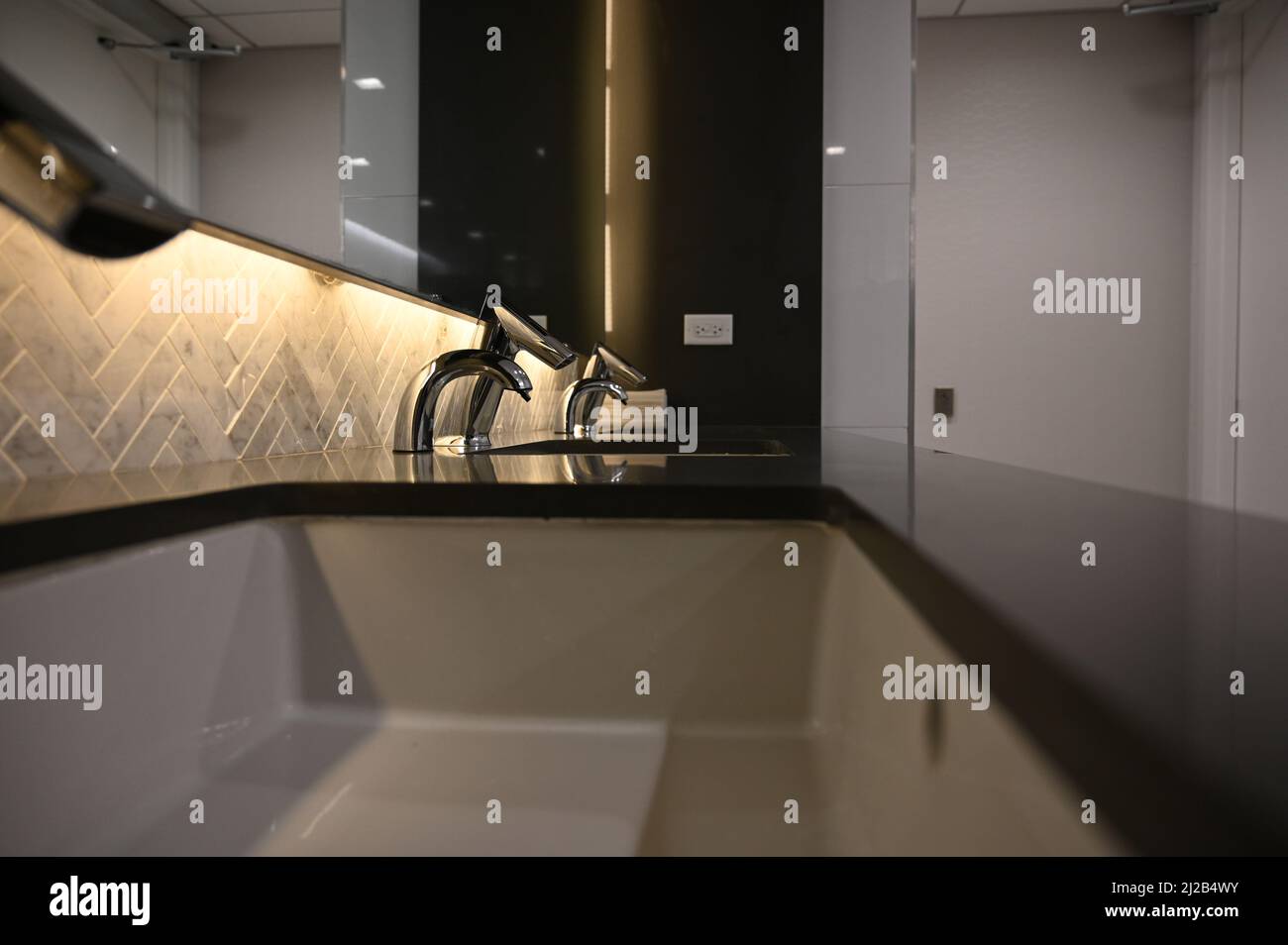 A clean kitchen cupboard area with shiny sinks and lights under the ...