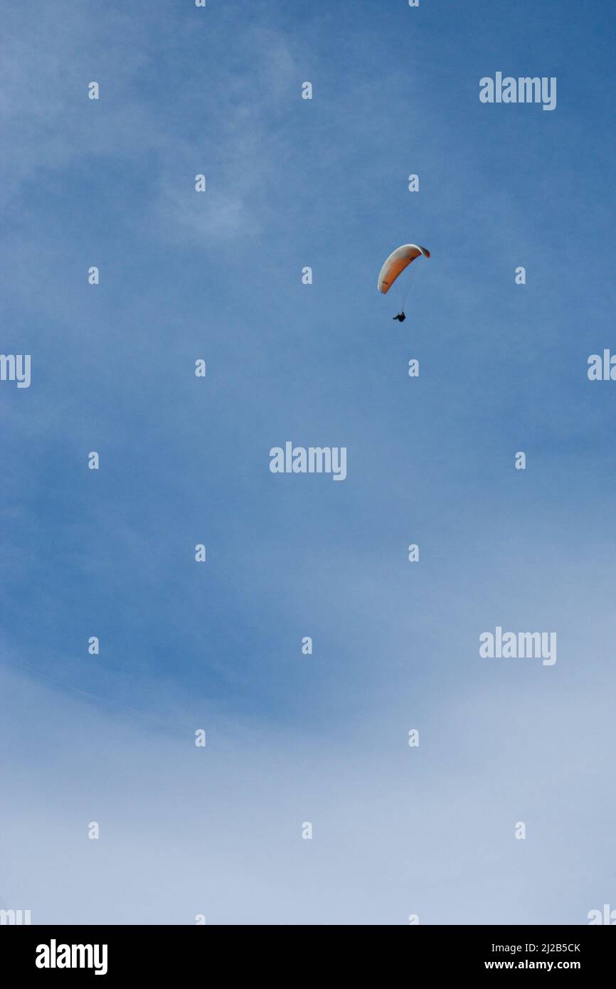 A low angle shot of a person paragliding on a cloudy sky background ...