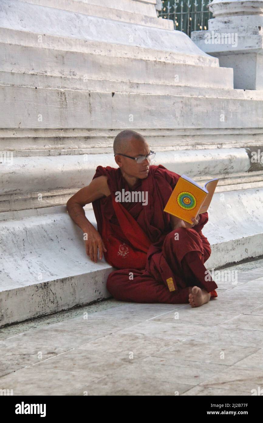 A vertical shot of a monk reading a book in Shwedagon Pagoda Stock ...