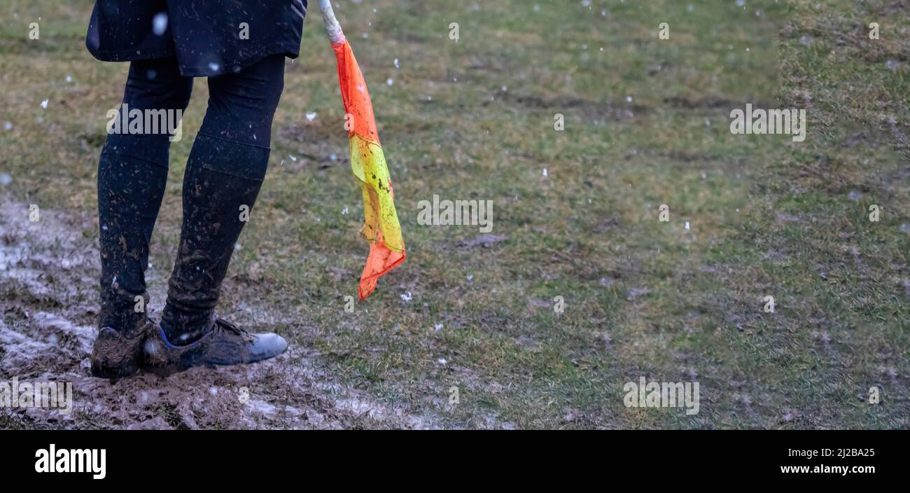 Football soccer arbiter assistant with flag at hands. Blurred green ...