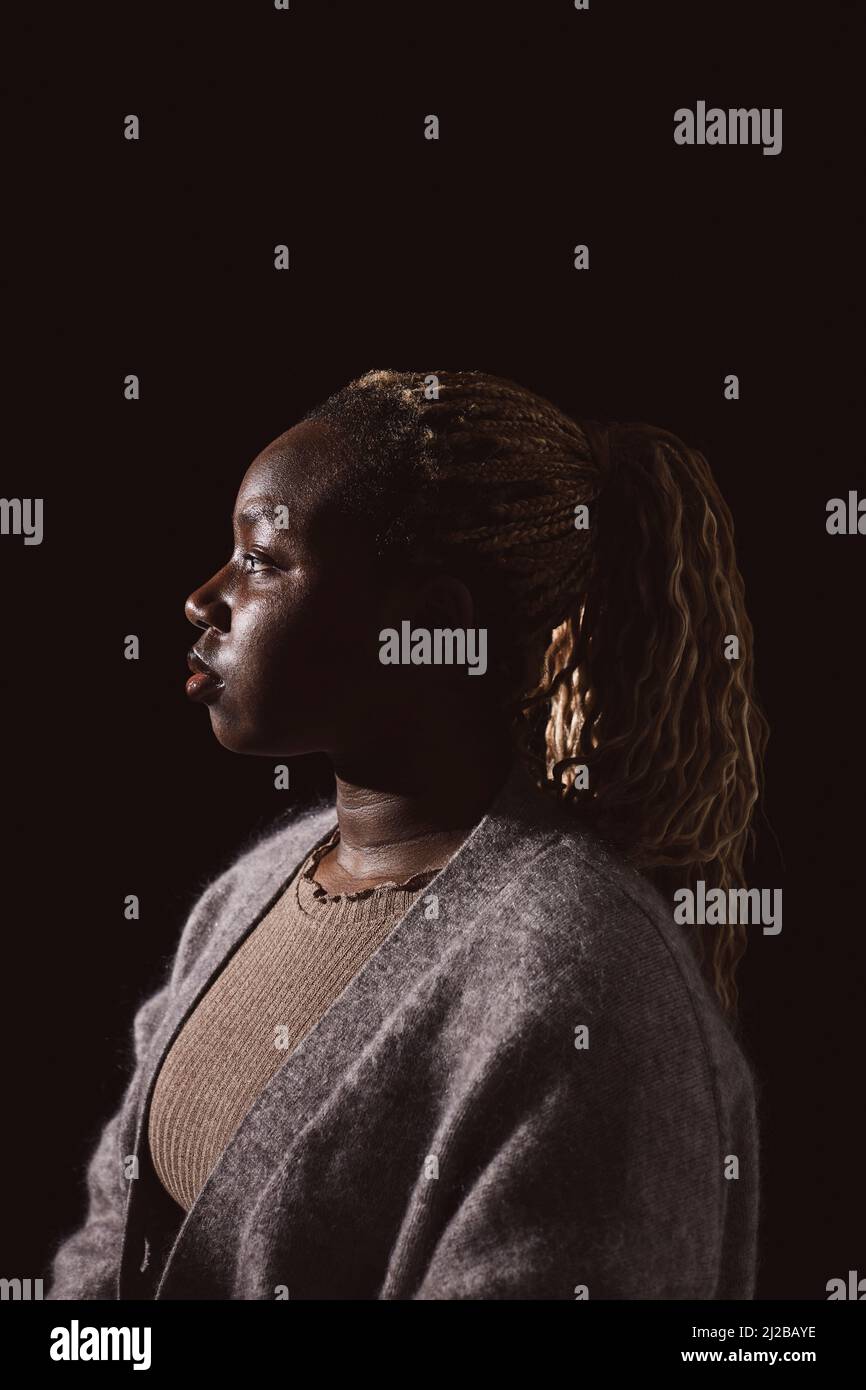 Contemplative woman by black background in studio Stock Photo - Alamy