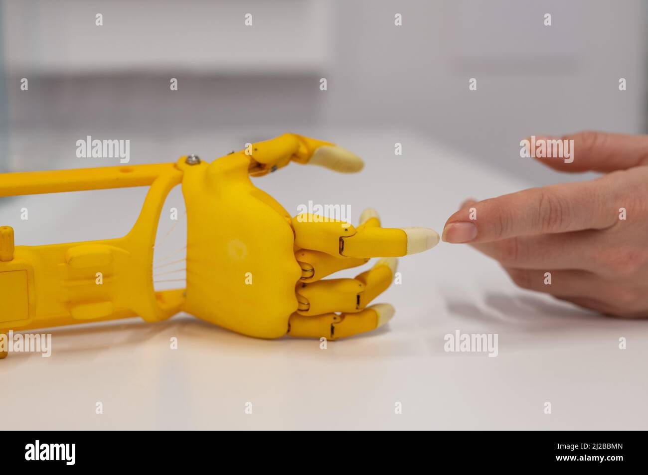 Woman's hand and a plastic hand prosthesis for a child on a white ...
