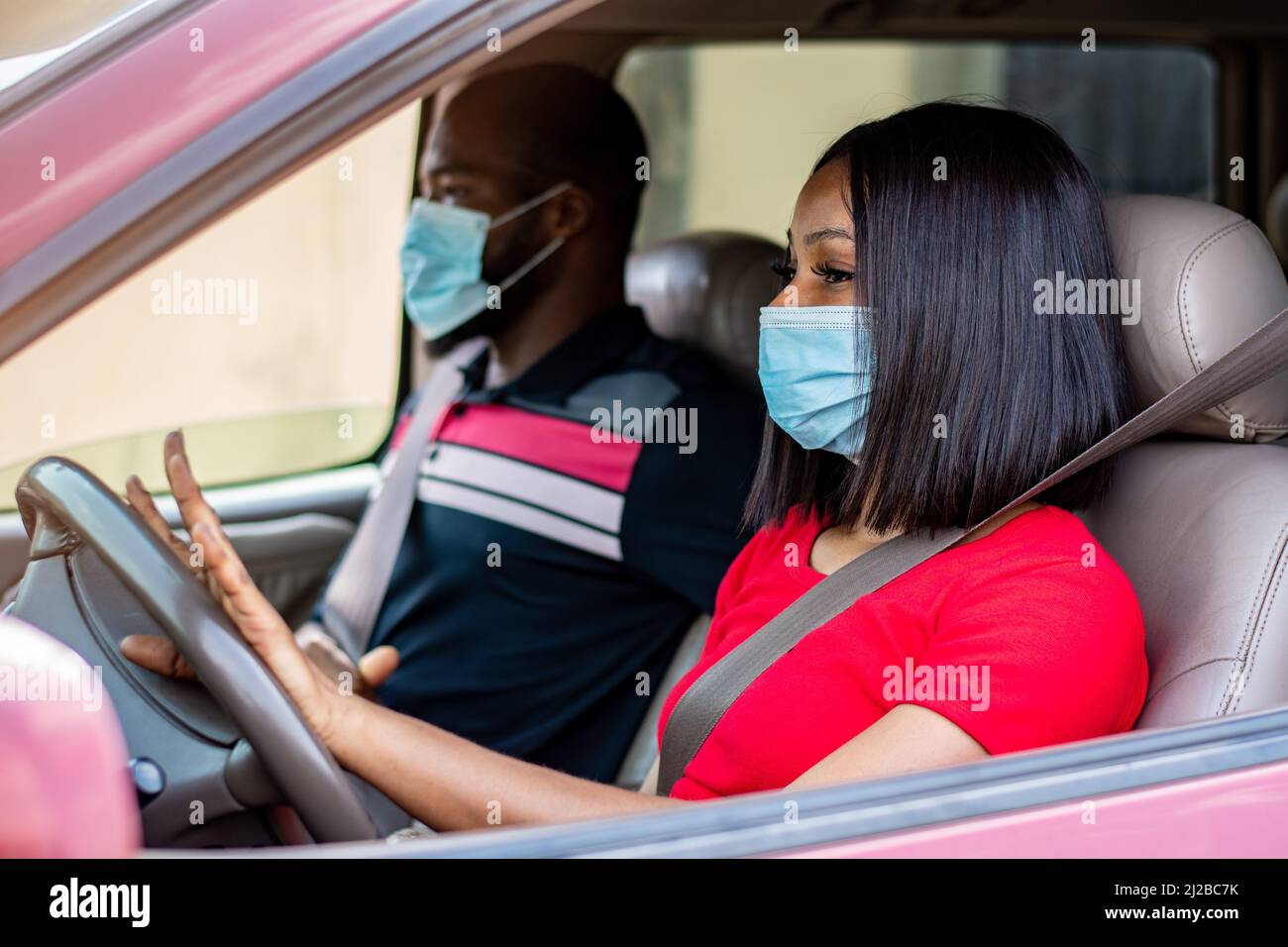 A closeup of the African woman and man wearing face masks while driving ...