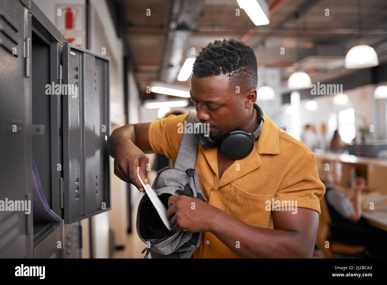 A young black student packs his notebooks into backpack at campus ...