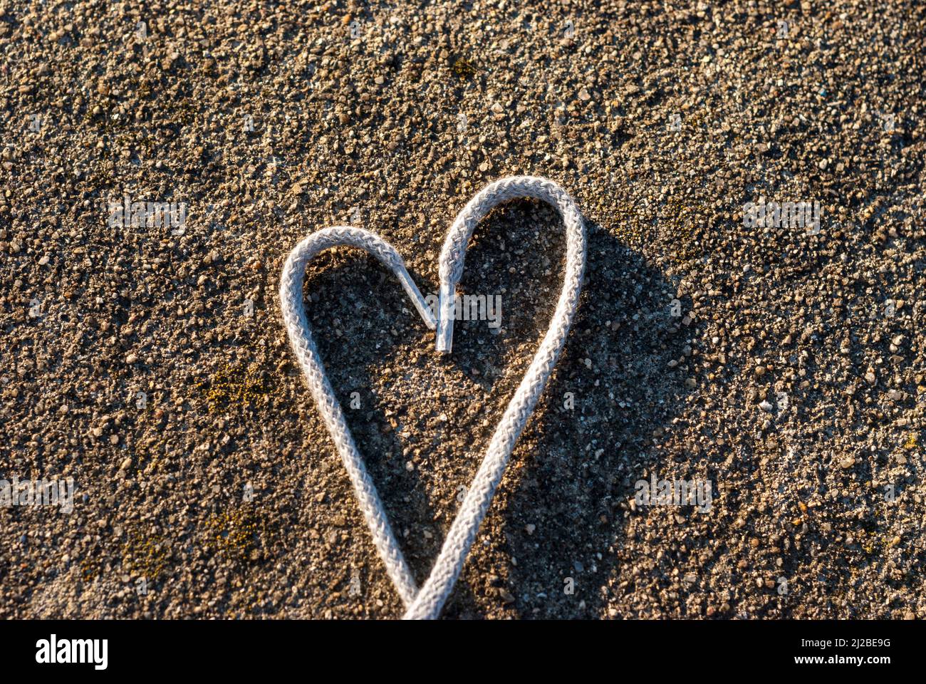 Shiny white heart with rope on gray table with light horizontal Stock ...
