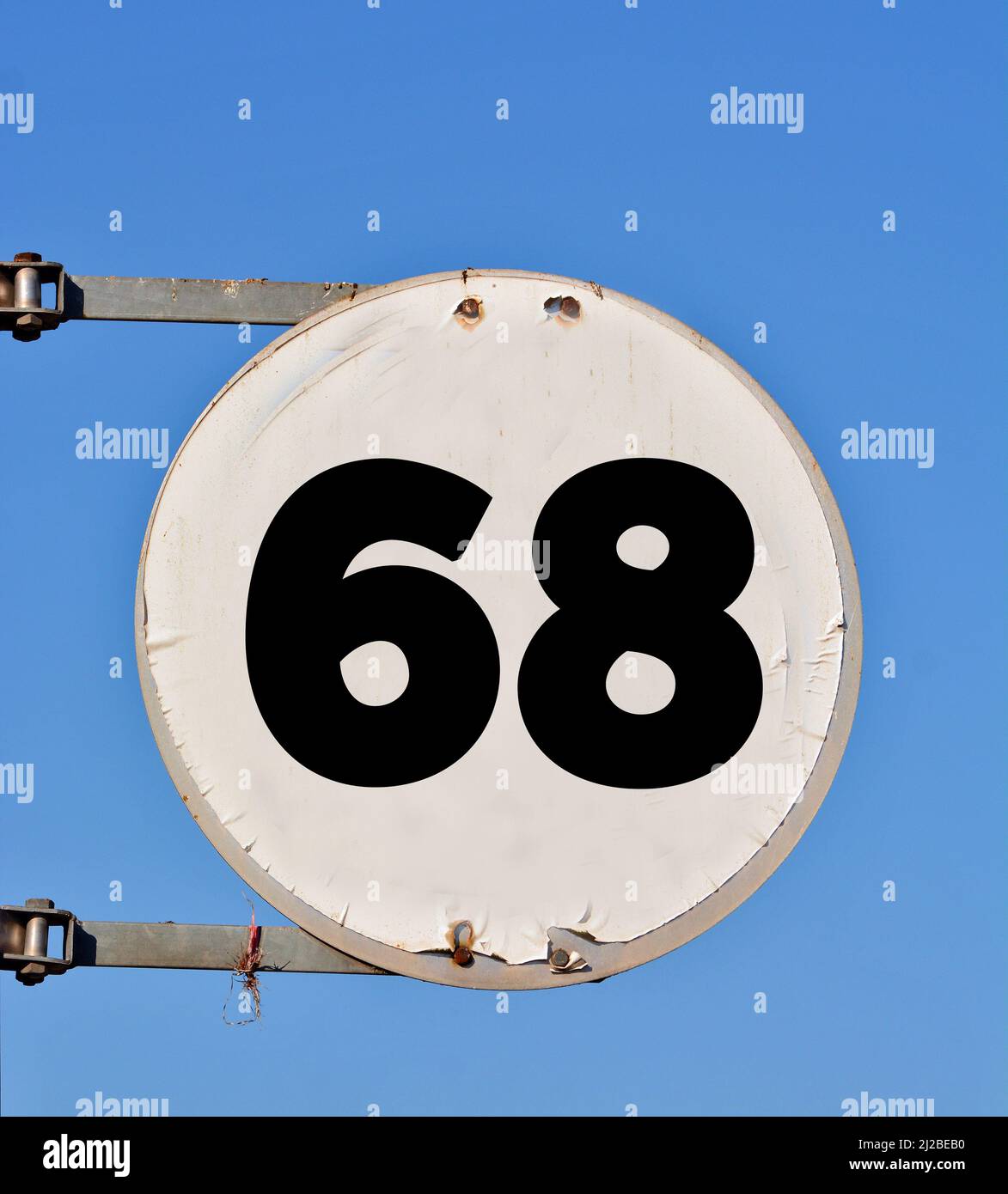 A speed limit sign with number 68 added on it against a blue sky Stock ...