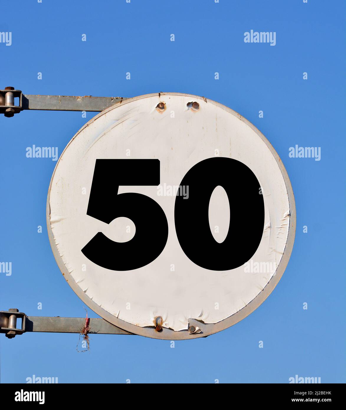 A speed limit sign with number 50 added on it against a blue sky Stock ...