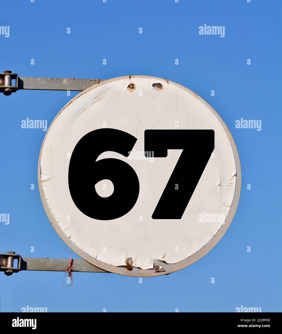 A speed limit sign with number 67 added on it against a blue sky Stock ...