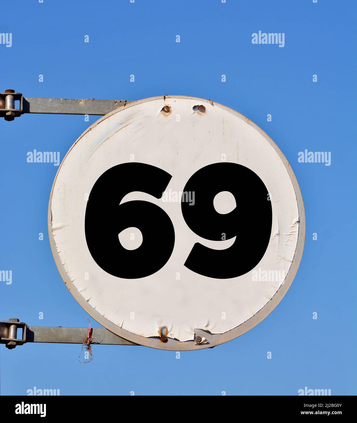 A speed limit sign with number 69 added on it against a blue sky Stock ...