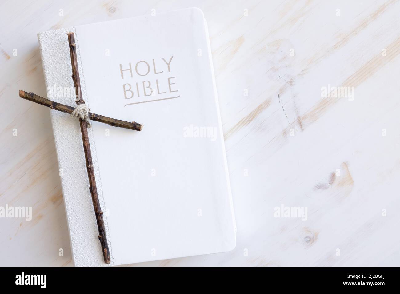 Simple wood cross on a closed white holy bible on a white wood ...