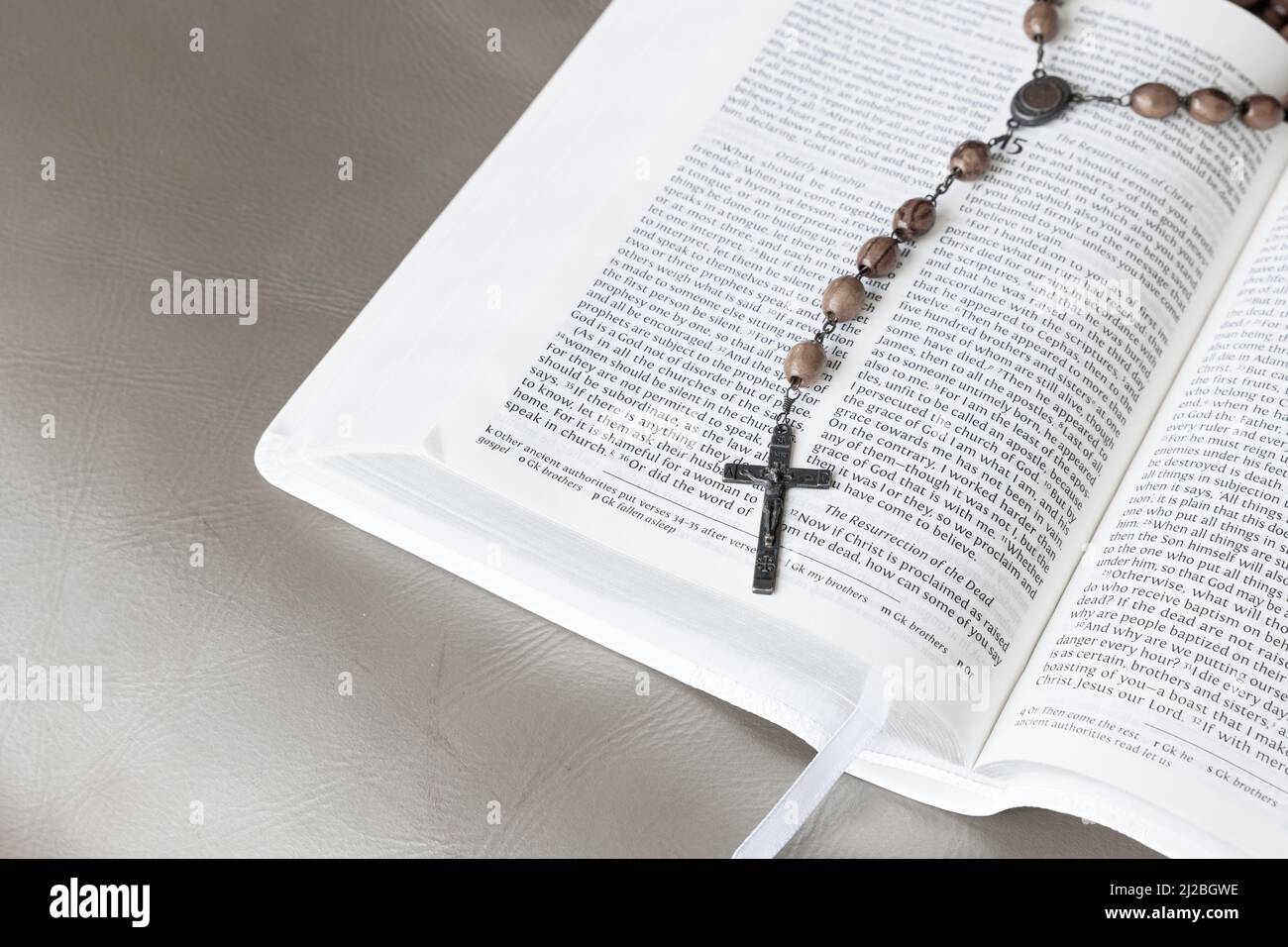 Rosary Catholic prayer beads laying on an open bible with copy space ...