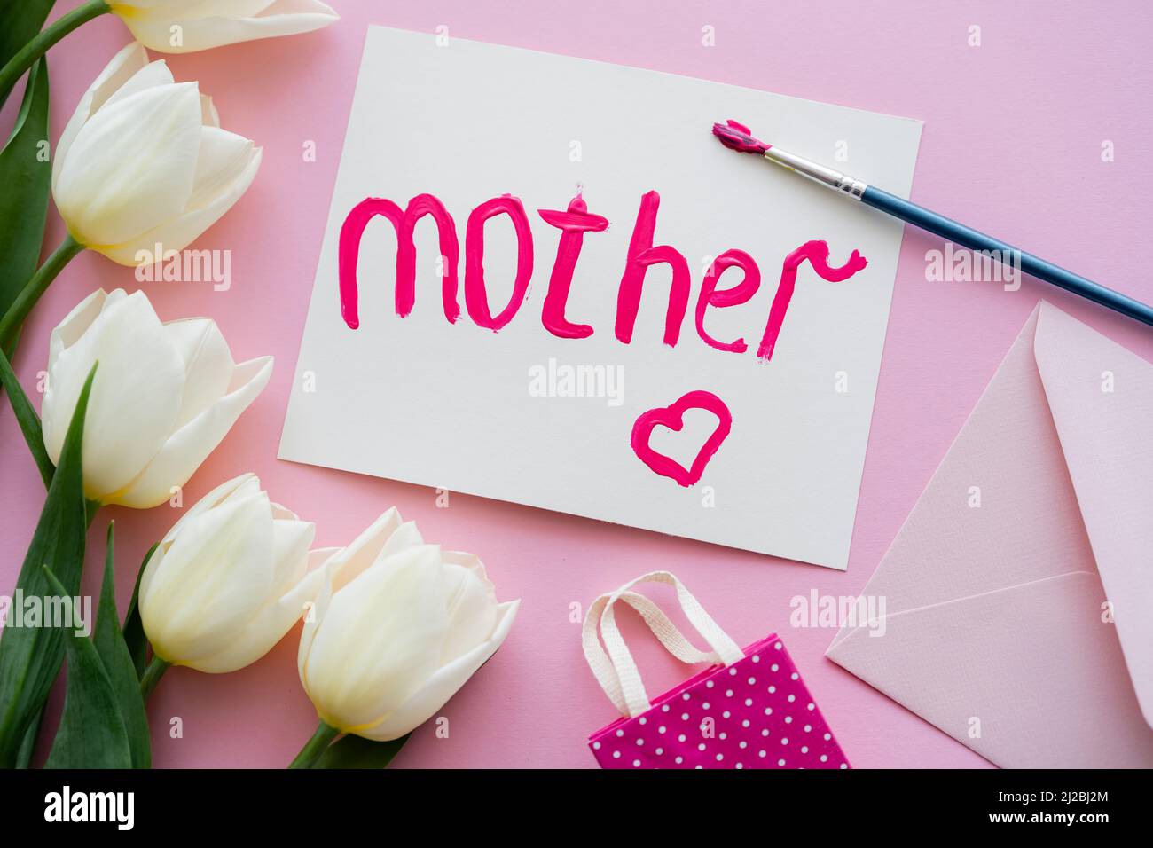 top view of paintbrush with paint near card with mother lettering and ...