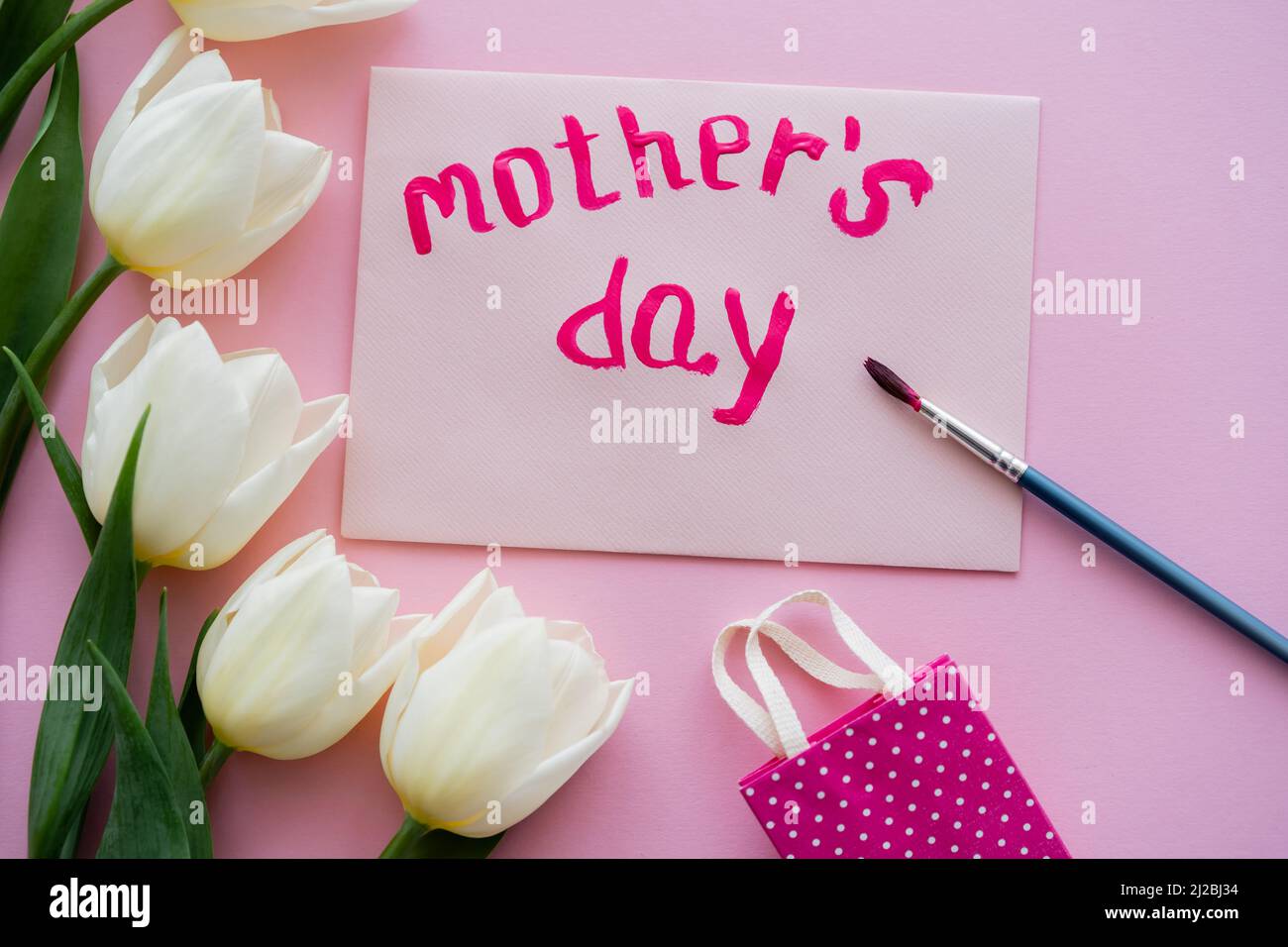 top view of paintbrush near card with mothers day lettering and white ...