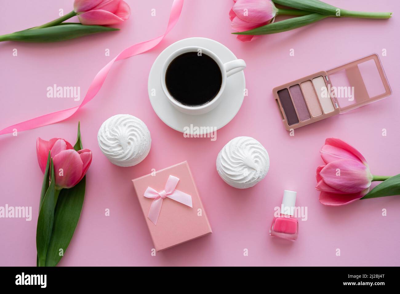 top view of zephyr, decorative cosmetics and tulips near cup of coffee ...