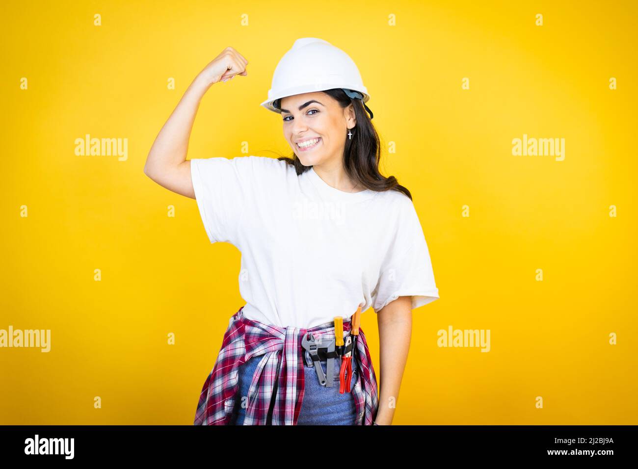 Young caucasian woman wearing hardhat and builder clothes over isolated ...