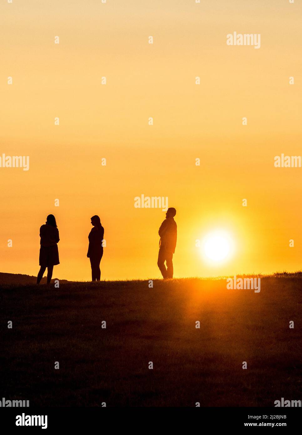 UK, England, Devonshire. A group of people watching the sunset from the ...