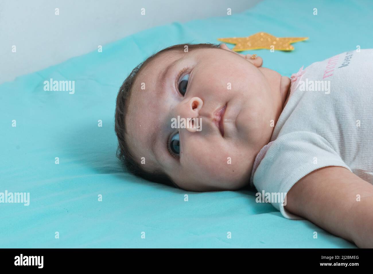 close up of beautiful two month old latina baby girl lying on a blue ...