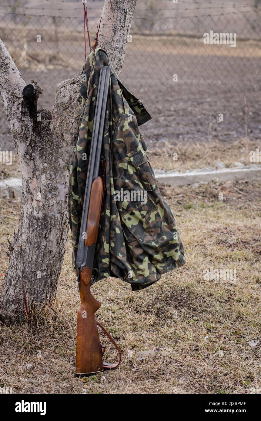 camouflage jacket hanging on tree near rifle in woods Stock Photo - Alamy