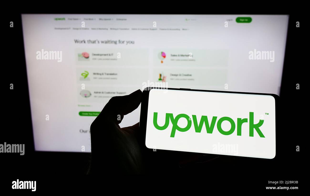 Person holding mobile phone with logo of American freelancing platform Upwork Global Inc. on ...