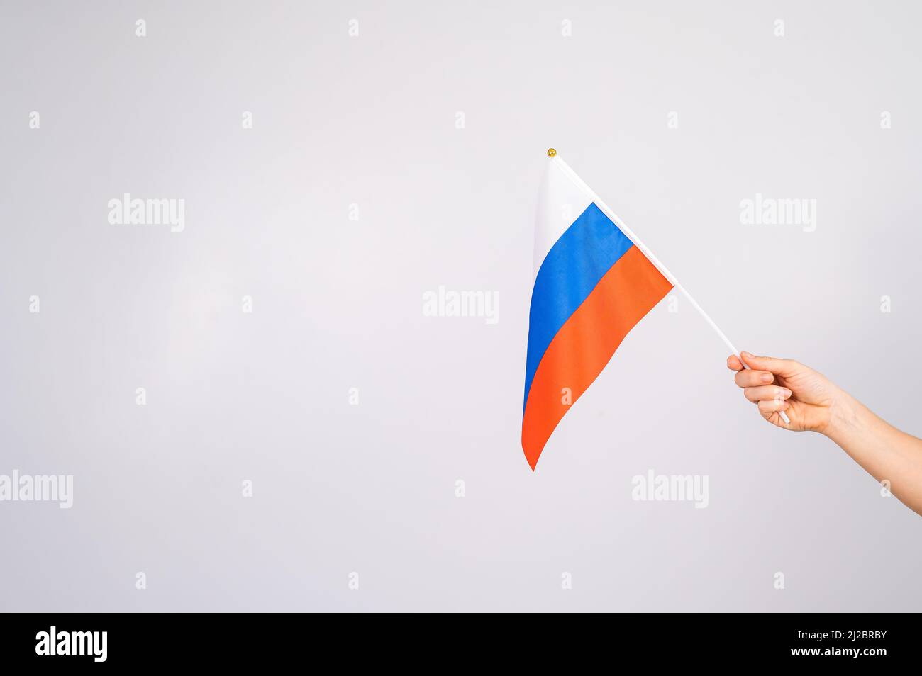 Woman holding a small flag of the Russian Federation on a white ...