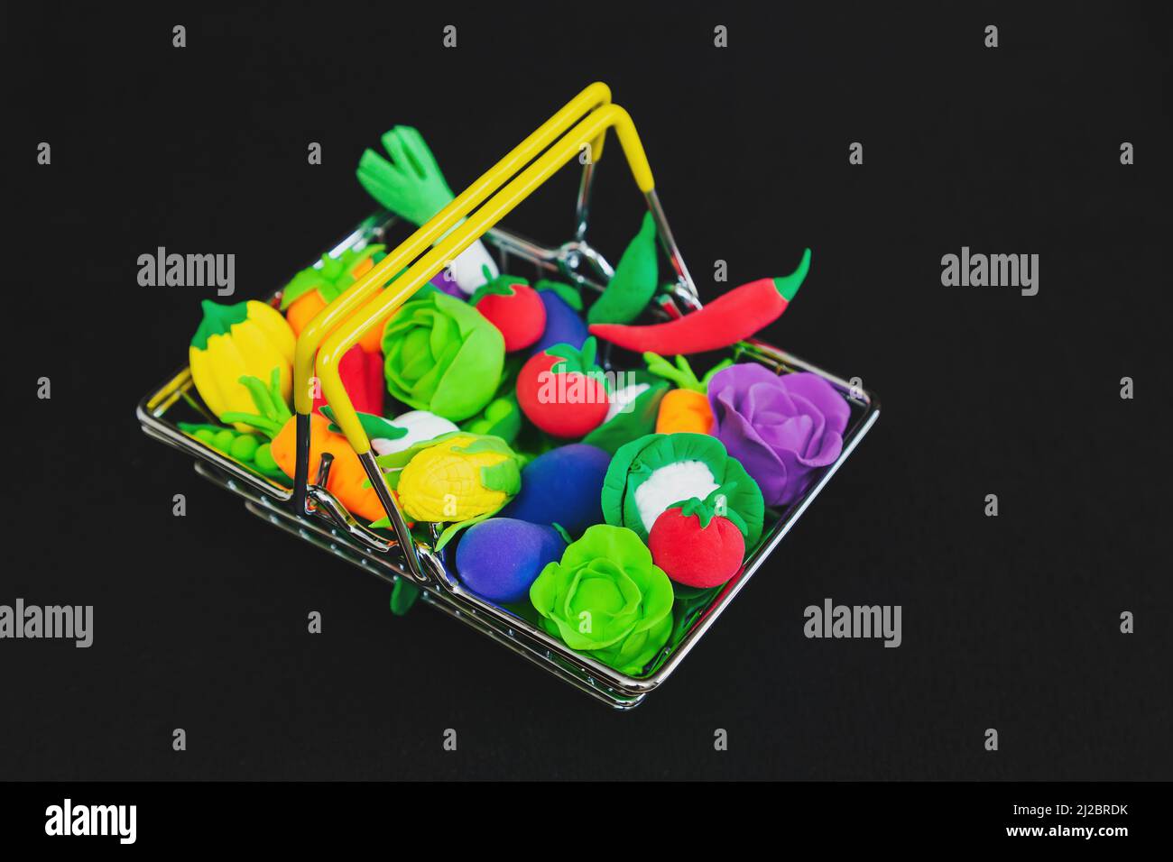 Different plasticine vegetables in a shopping basket on a black ...