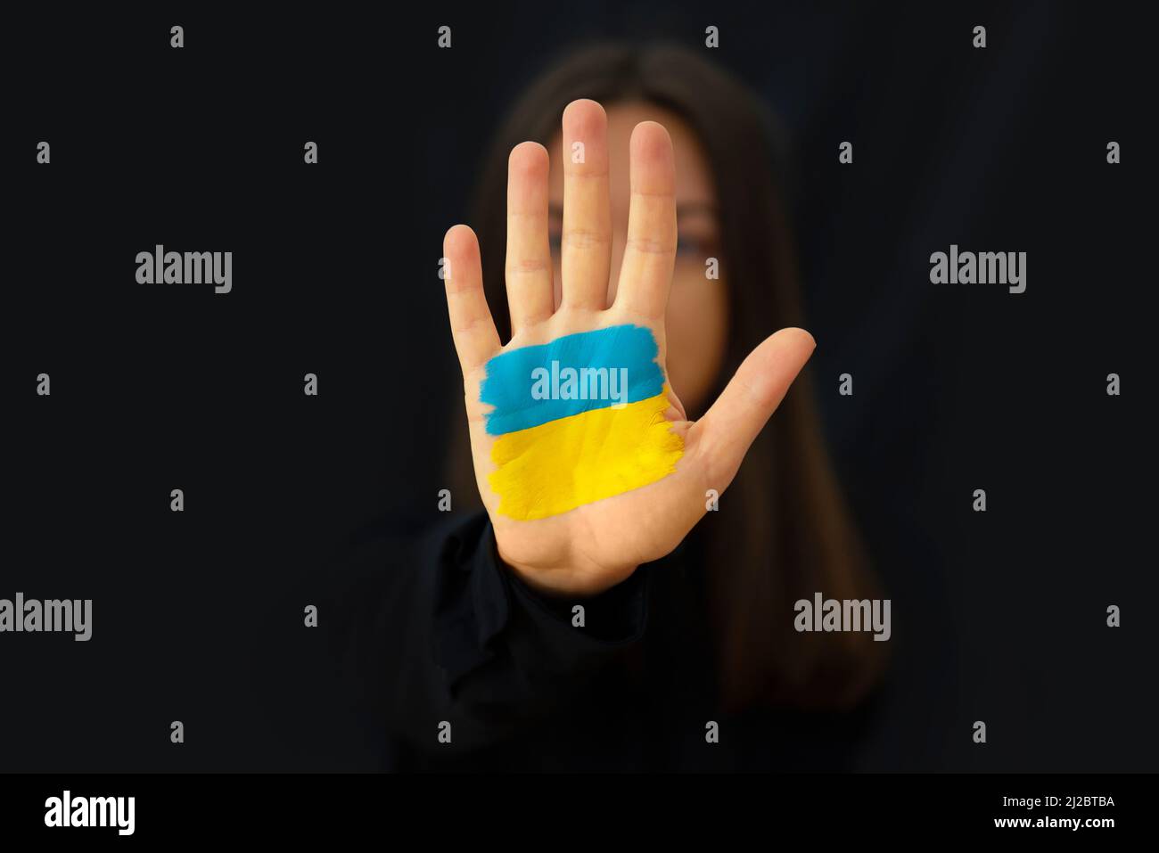 Girl with a stop gesture shows the Ukrainian flag in the palm of her ...