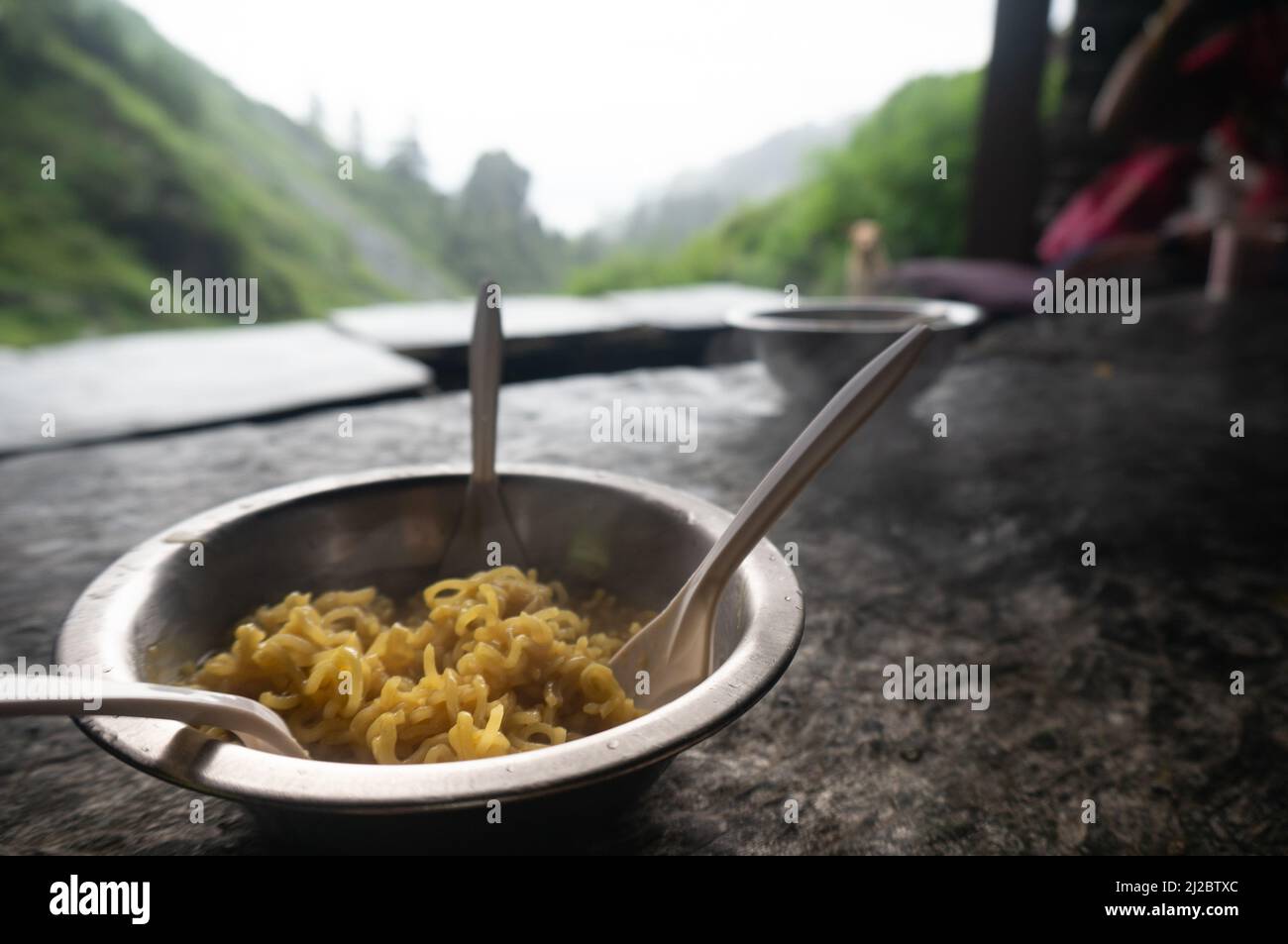 instant noodles like maggi served in steel plate bowl with forks staple ...