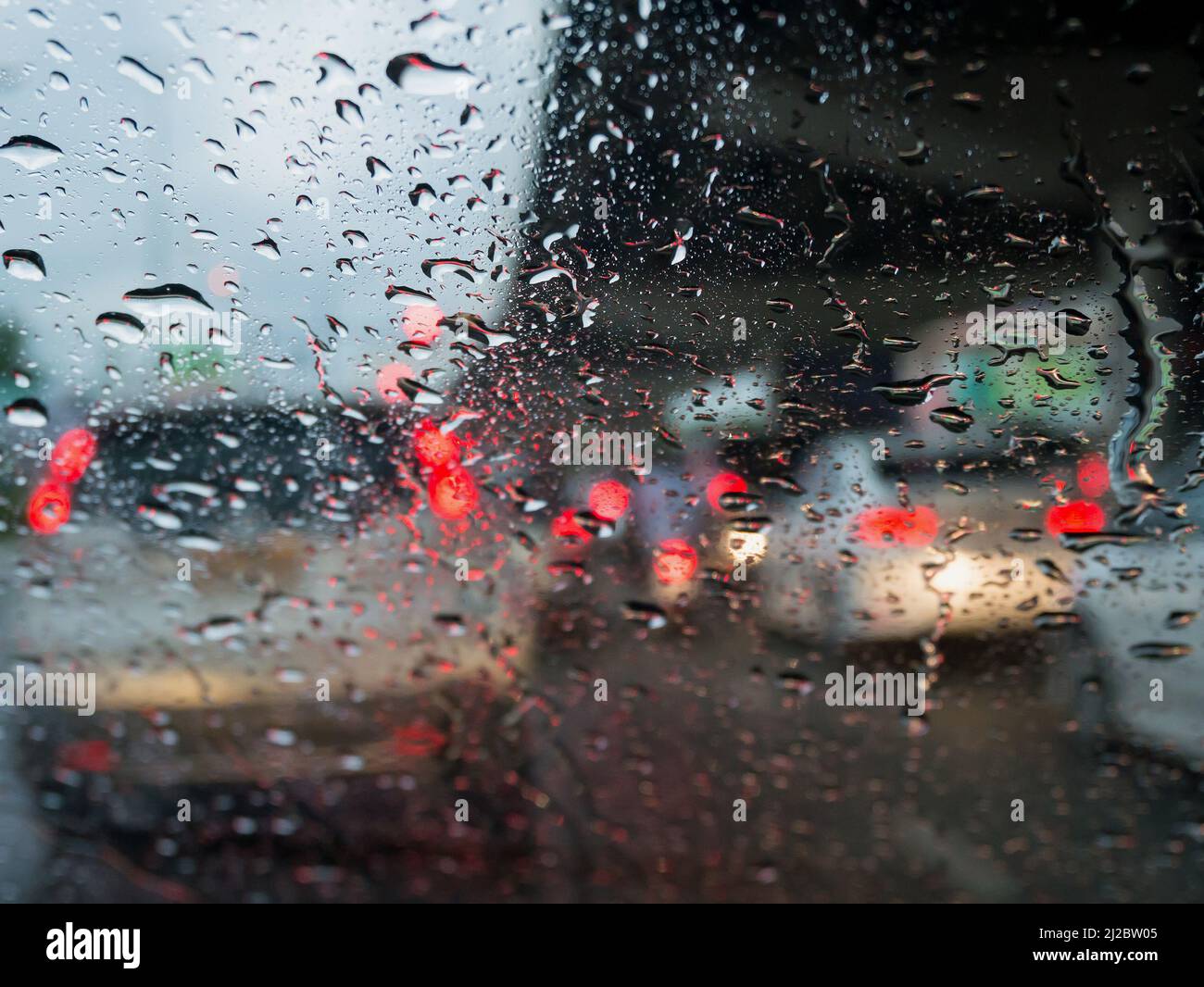 Traffic in rainy day with road view through car window with rain drops ...