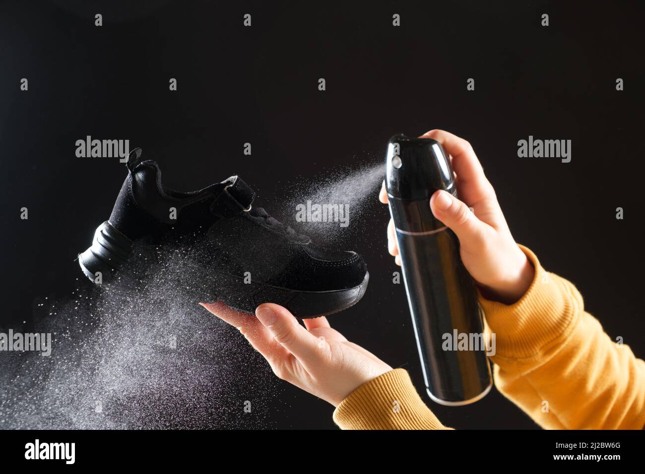 A woman applies a spray from a cylinder with a water-repellent liquid ...