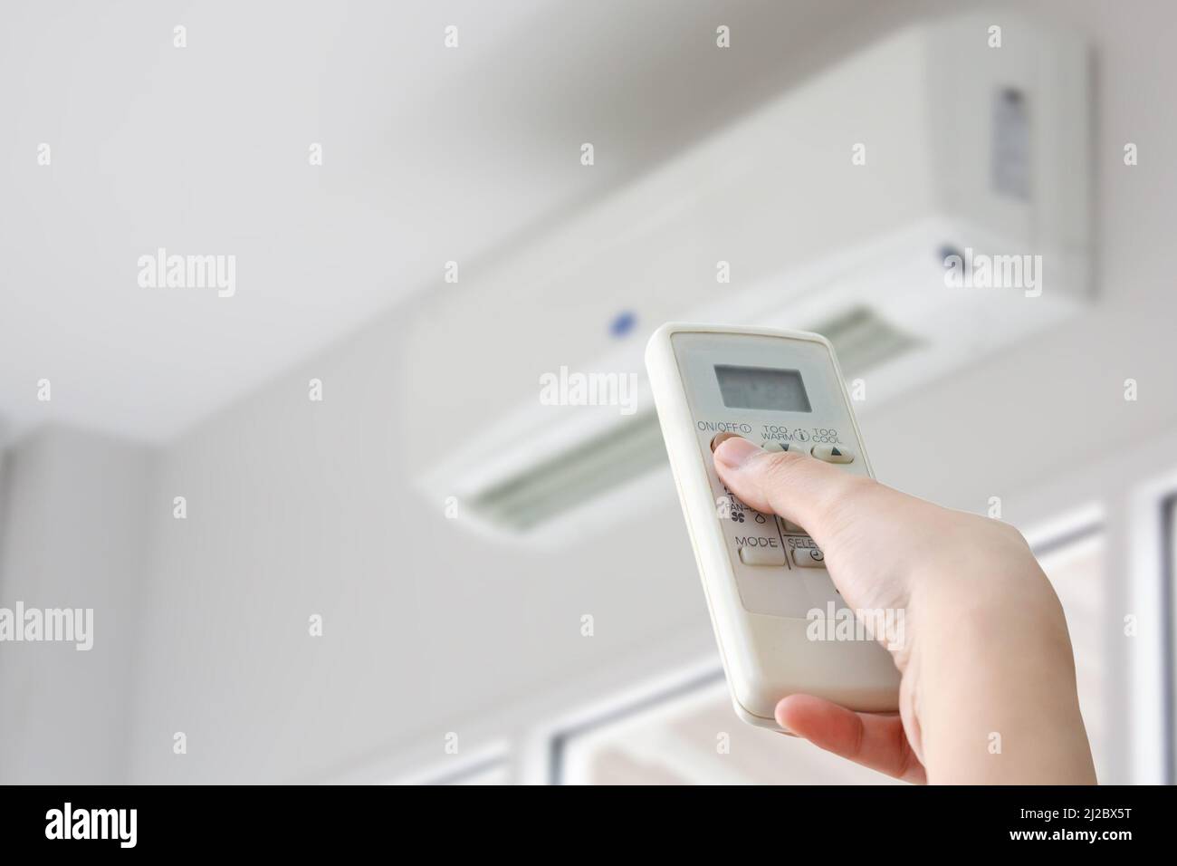 Hand with remote control directed on air conditioner Stock Photo - Alamy