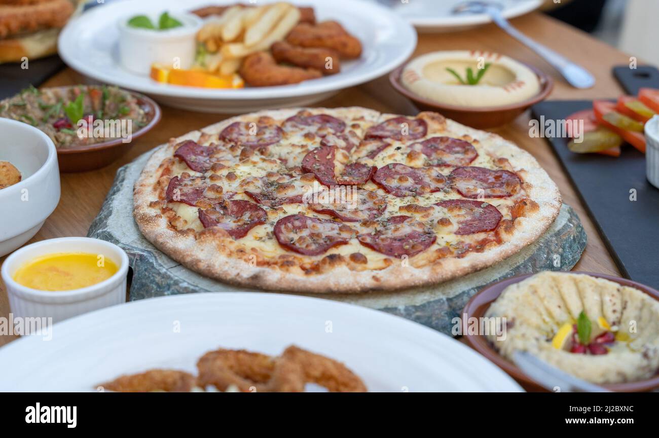 pepperoni pizza with along with other arab cuisine items on the table ...