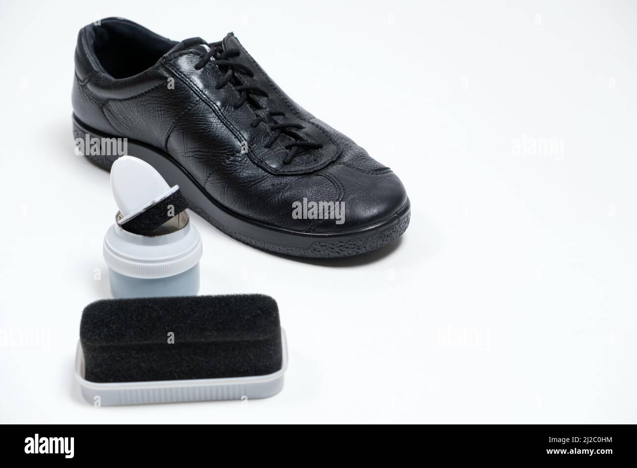 Shoe cream with sponge and black men's leather shoes on a white ...