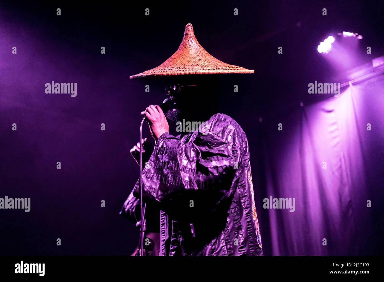 An African singer in an asian hat performing live on a stage with ...