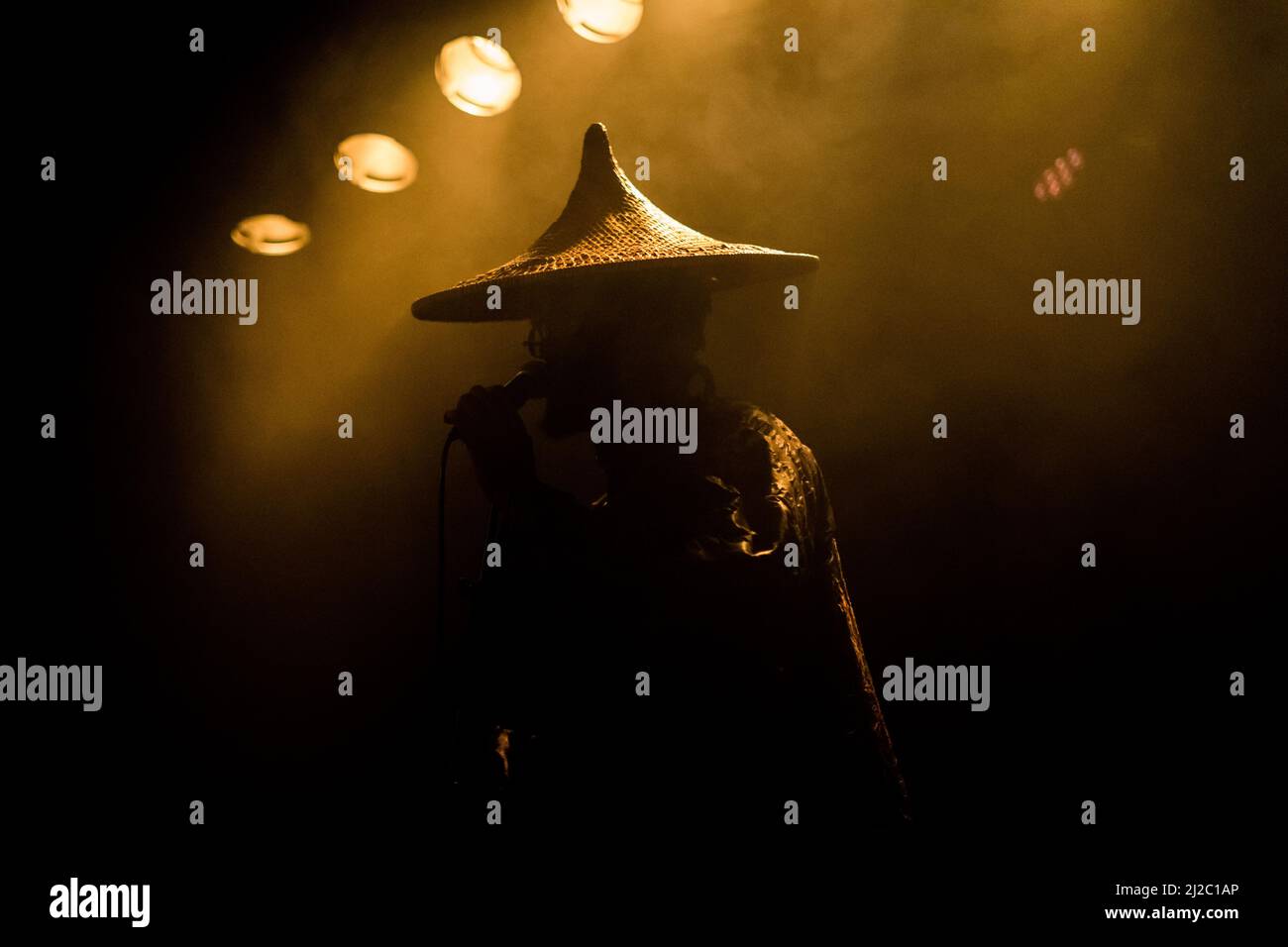 An African singer in an asian hat performing live on a stage with ...