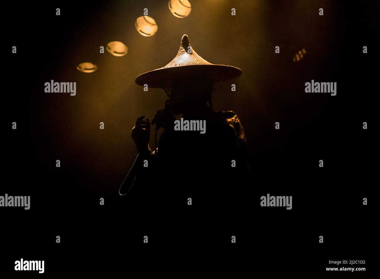 An African singer in an asian hat performing live on a stage with ...
