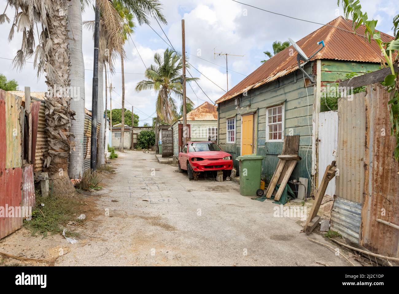 Side street with small weathered house and a broken red car in the ...
